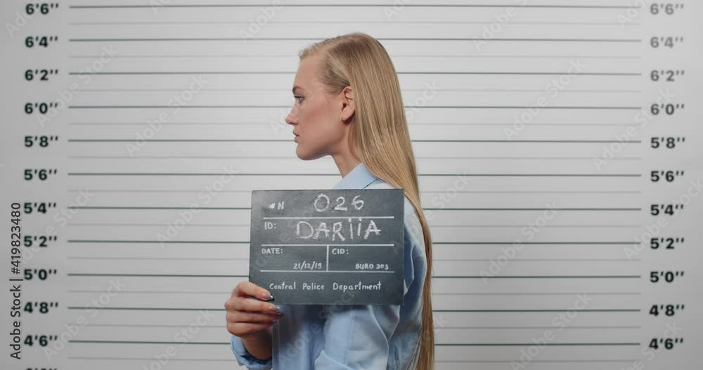 Mugshot of attractive woman holding sign for photo in police department ...