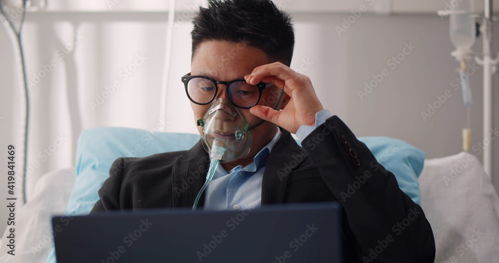 Tired sick businessman lying in hospital bed wearing suit and oxygen ...