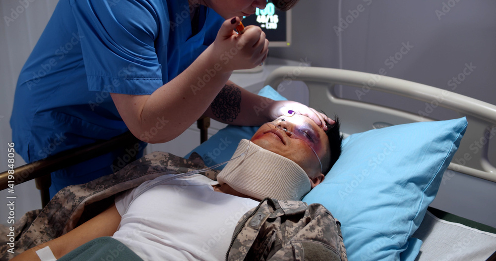 Doctor checking condition of unconscious injured soldier in hospital ...