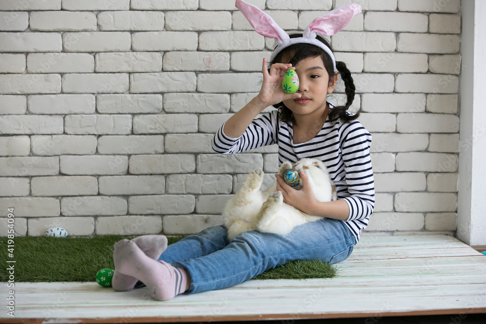 Cute girl is wearing bunny ears sitting in the room and holding her ...