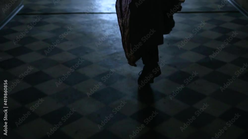 A silhouette of a man running across the tile floor along a dark ...
