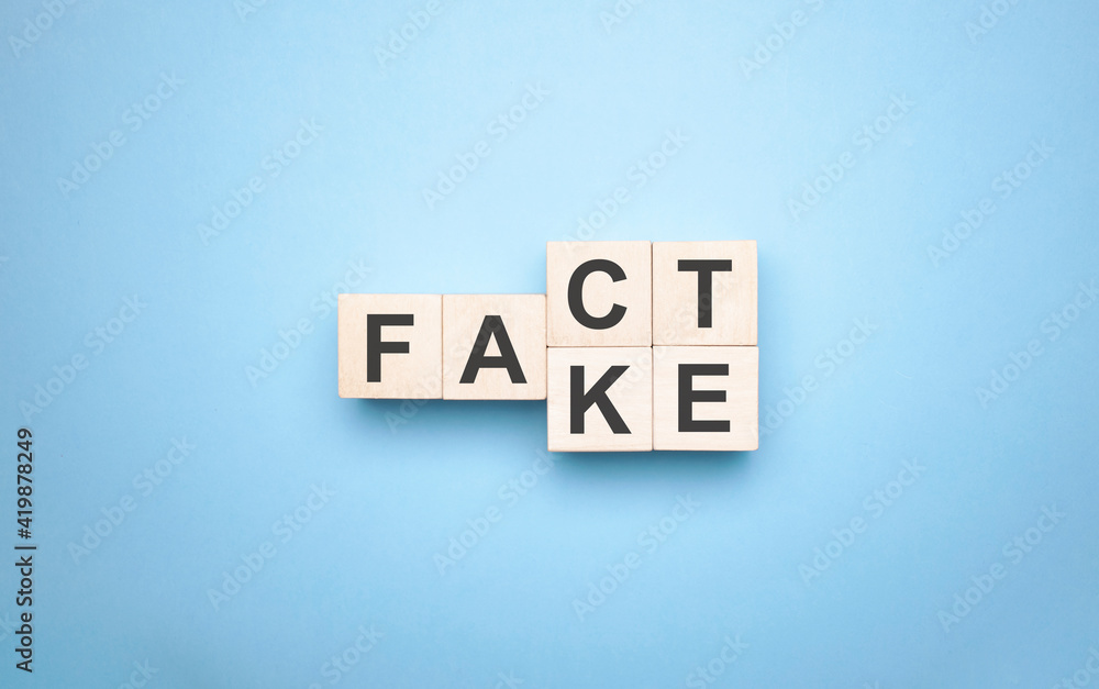 Wooden blocks with letters forming words Fact and Fake on blue ...