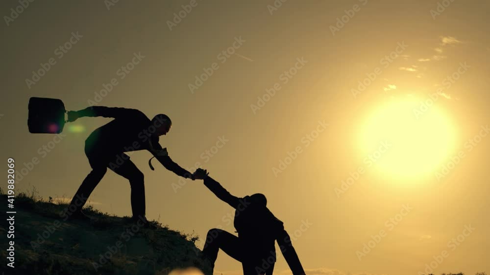 Stockvideon Two businessmen climb to top of mountain. Helping hand in ...
