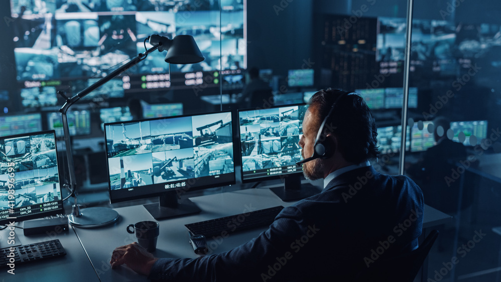 Male Officer Works on a Computer with Surveillance CCTV Video in a ...