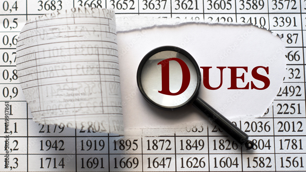 DUES - word behind torn paper with numbers on a white background with a ...