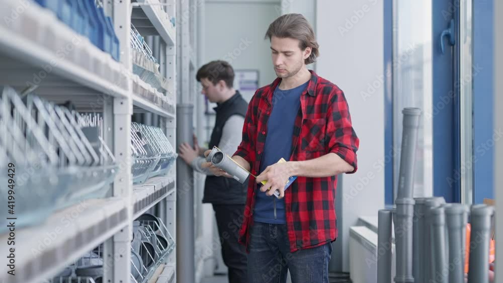Vidéo Stock Concentrated man measuring pipe connector in hardware store ...