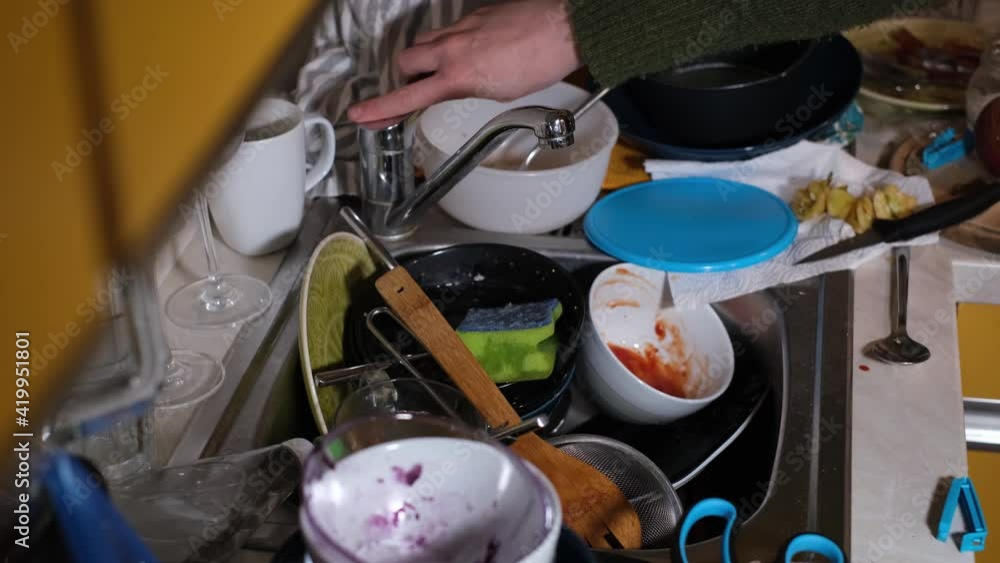 A housewife opening the water tap before washing dishes and cleaning ...