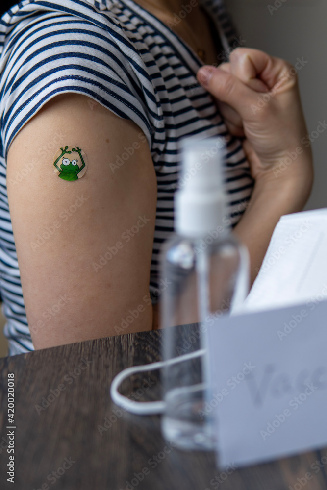 Arm of a woman with a colorful adhesive bandage after injection of ...