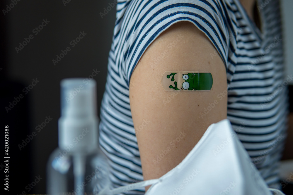 Arm of a woman with a colorful adhesive bandage after injection of ...