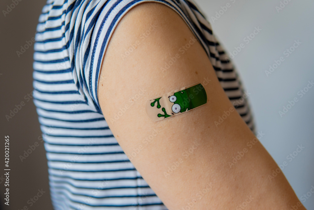 An arm of a woman with a fun, colorful, adhesive bandage after ...