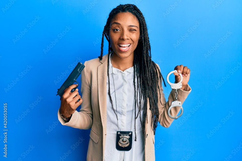 African American Police Woman Holding Gun And Handcuffs Winking Looking