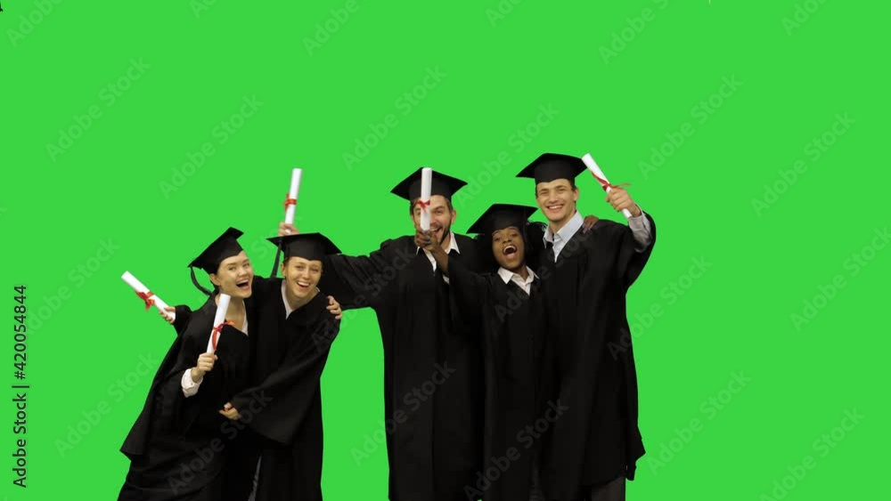 Happy students in graduation gowns posing for a picture on a Green ...