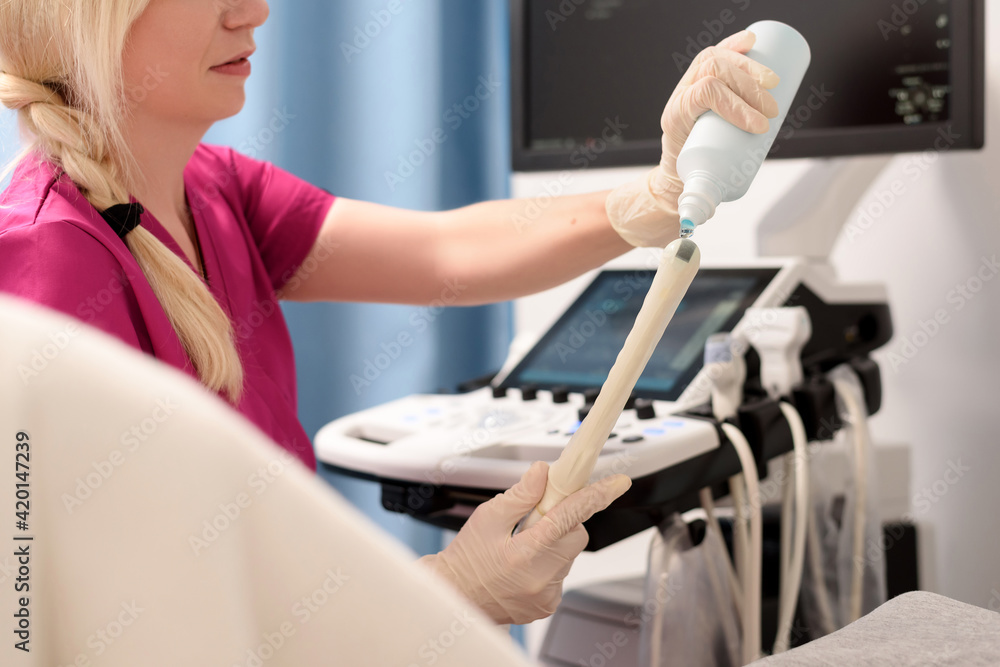 Gynecologist applies gel to a transvaginal ultrasound scanner for a ...