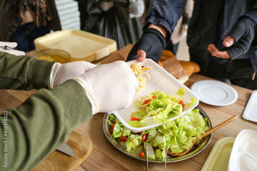 Volunteer giving food to homeless people in warming center Stock Photo ...