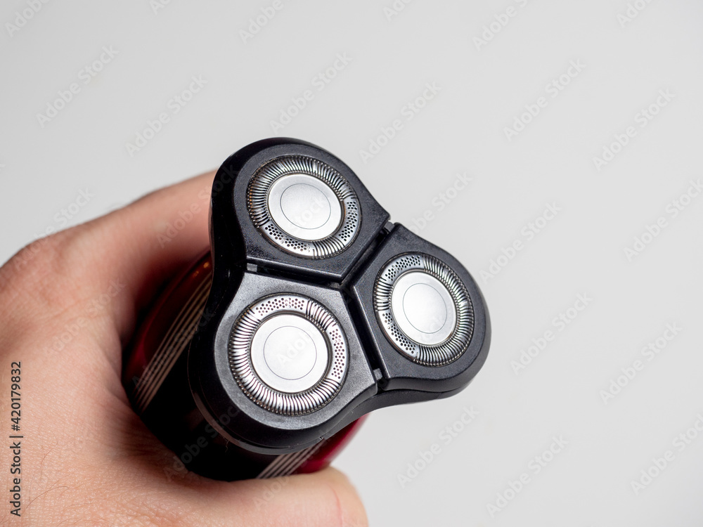 side view of an electric razor with three floating heads in a man's ...