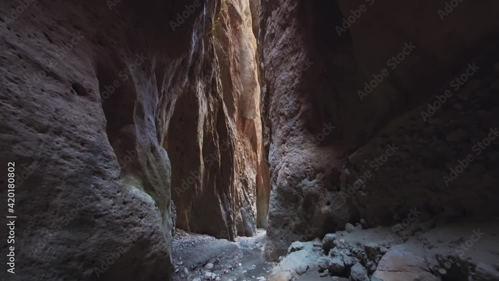 Gimbal forward walk through narrow dark gorge rift in ground, high epic ...