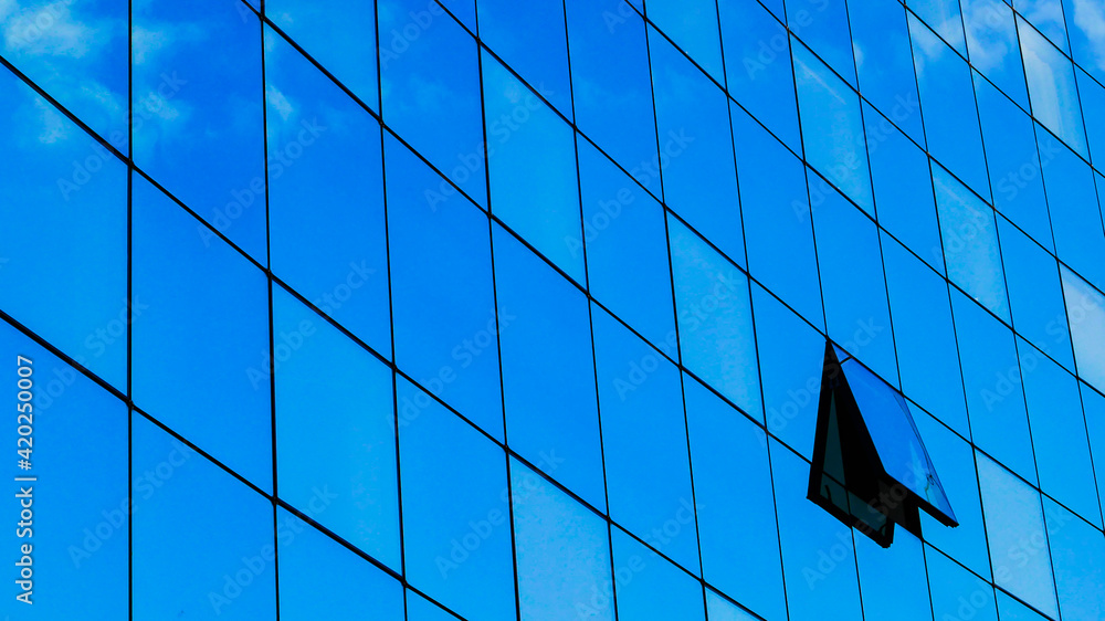 transparent glass wall of office building, sky and clouds reflecting on ...