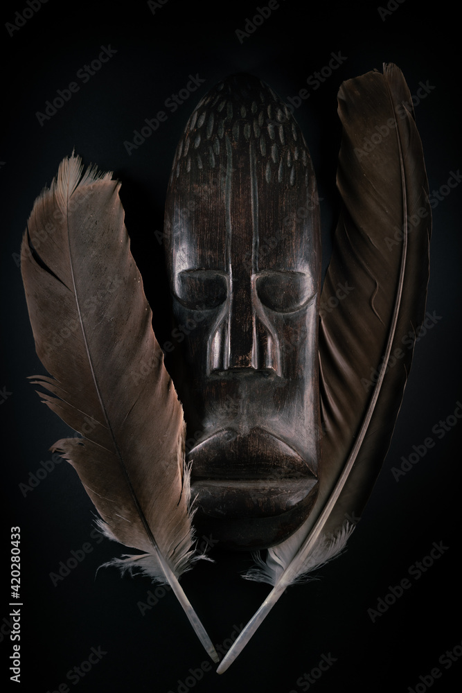 Wooden sculpture of human face in African style with big feathers ...