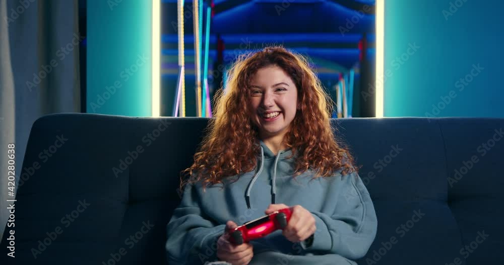 Lovely young woman playing video games pressing buttons quickly on ...