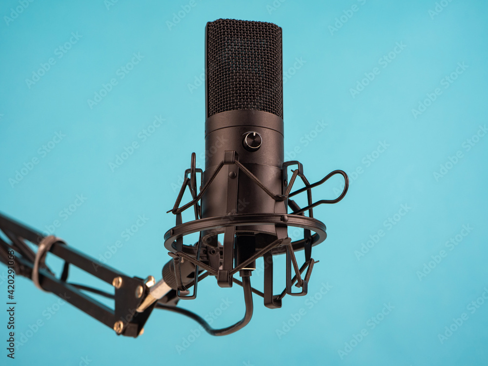 Studio condenser microphone close-up. It is mounted on a black stand ...