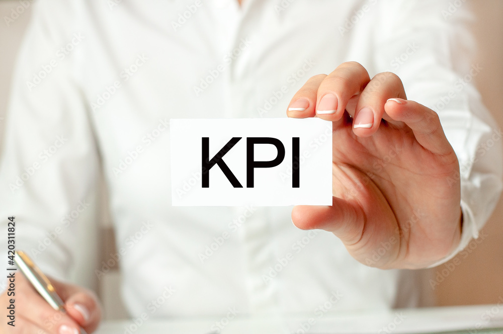 A woman in a white shirt holds a piece of paper with the text: KPI. KPI ...