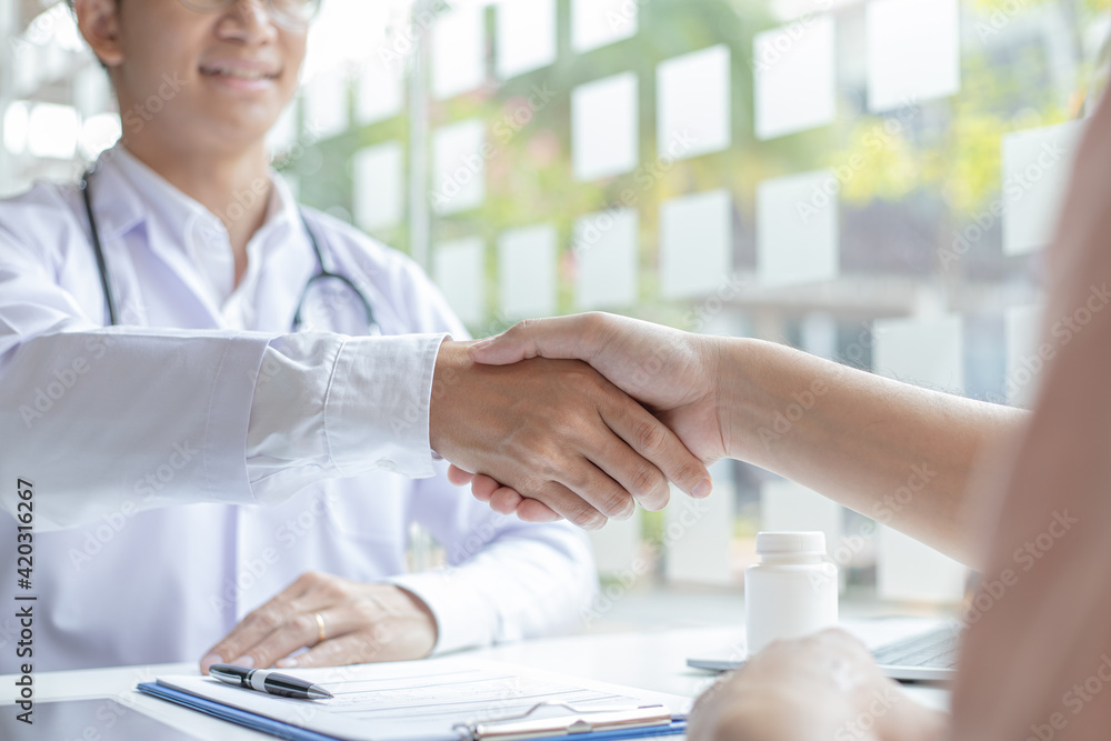 Two men holding hands, Asian doctor smiled shake hands with the patient ...