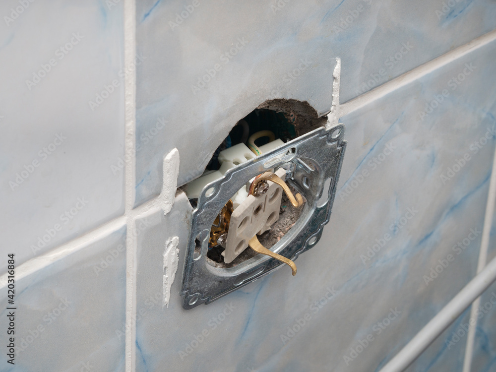 Disassembled, torn out electrical socket with bare wires in the ...