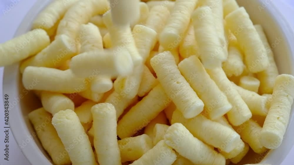 Vidéo Stock Corn puffs falling into a bowl, slow motion. Concept of ...
