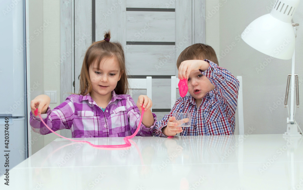 Little kids playing with pink slime at home. A fashionable liquid toy ...