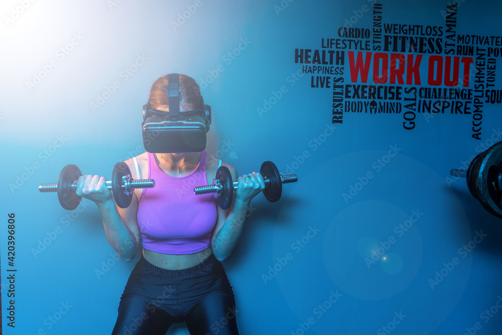 Attractive young red hair sportswoman training biceps in the gym of her ...