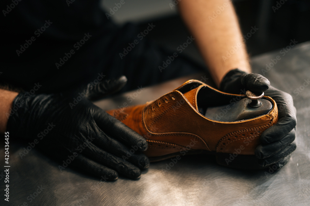 Close-up top view of hands of shoemaker shoemaker in black gloves ...