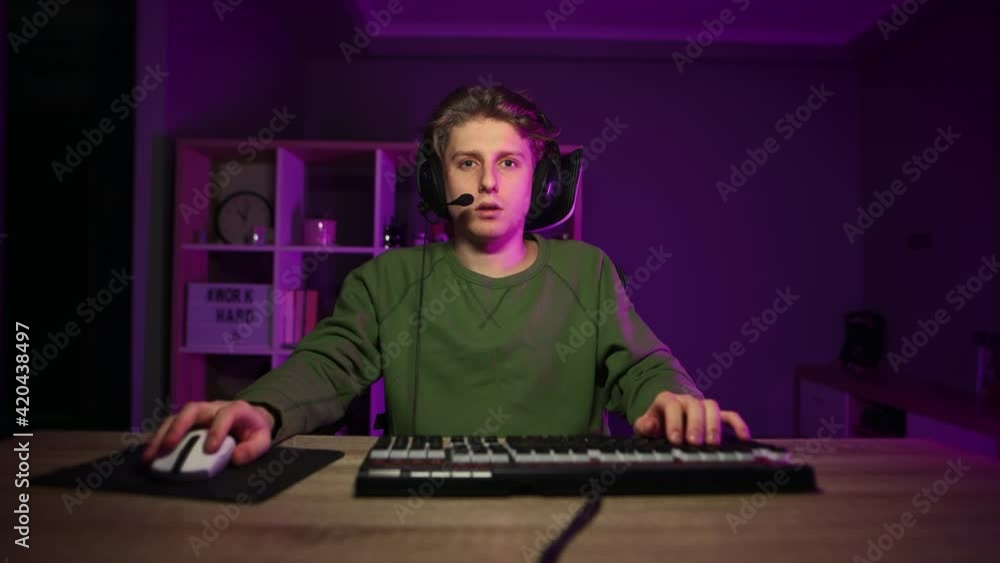 gamerPositive young e-athlete sits at home in a cozy room and trains in ...