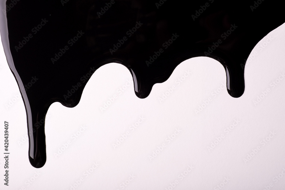 Black liquid drops of paint color flow down on isolated white ...
