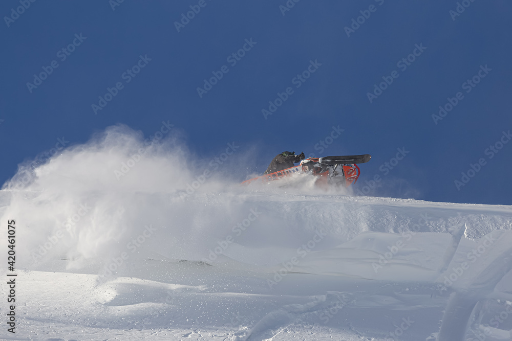 elite sports snowmobiler rides and jumps on steep mountain slope with ...