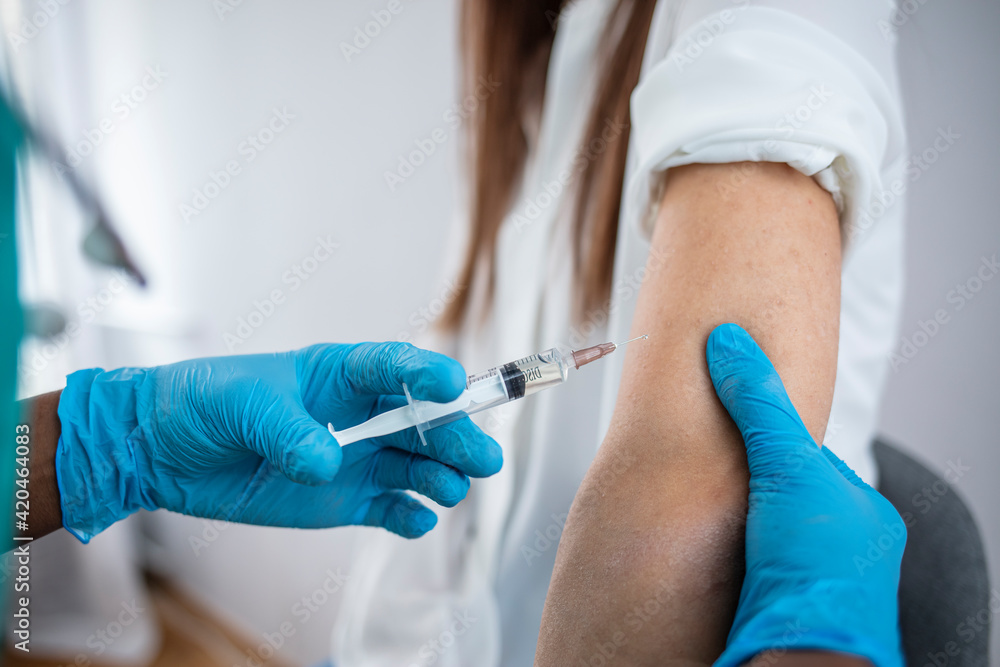 Close up of a Doctor making a vaccination in the shoulder of patient ...