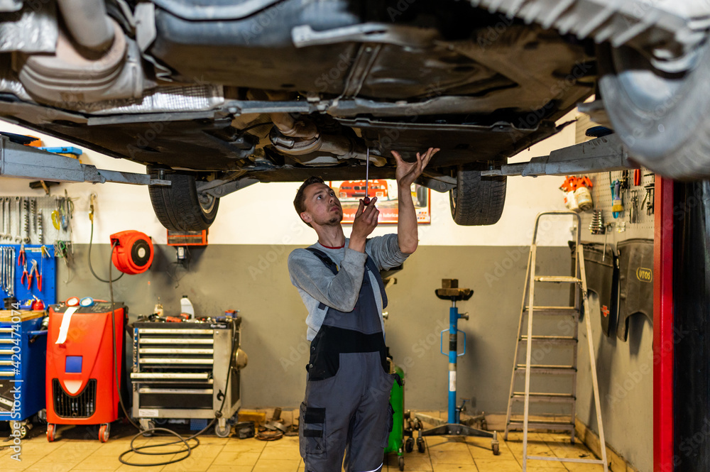 Car mechanic replacing fuel filter, in under the background car on a ...