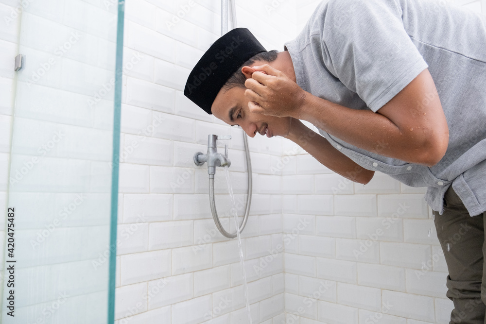 portrait of young Muslim man perform ablution (wudhu) before prayer at ...