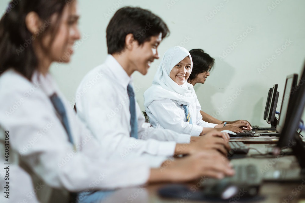 Indonesian high school students using computer pc with their friends ...