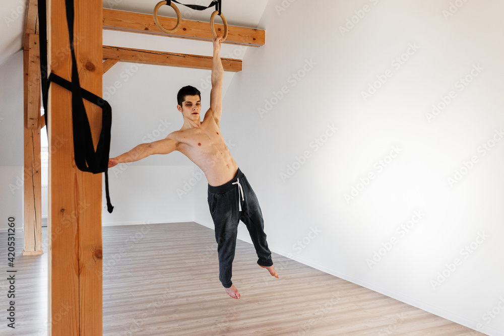 Strong gymnast hanging on ring in attic Stock Photo | Adobe Stock