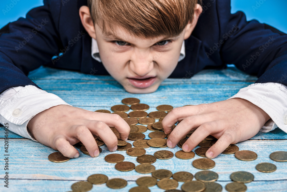 The greedy and greedy child covered the coins with his hands and looks ...