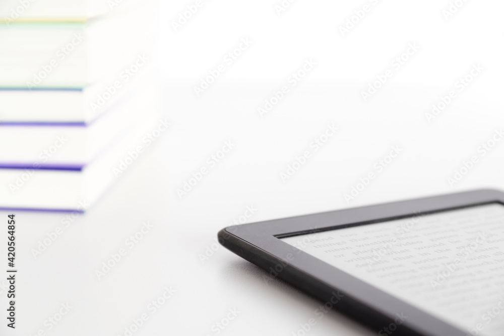 Corner of a stack of books and an electronic reader with a text on the ...