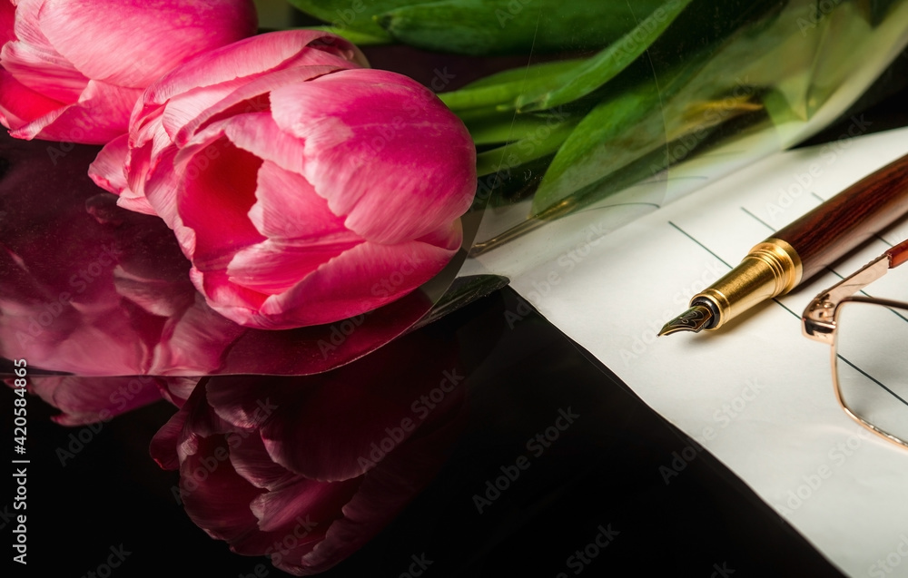 Stylish pen on a blank sheet of paper and flowers in transparent ...