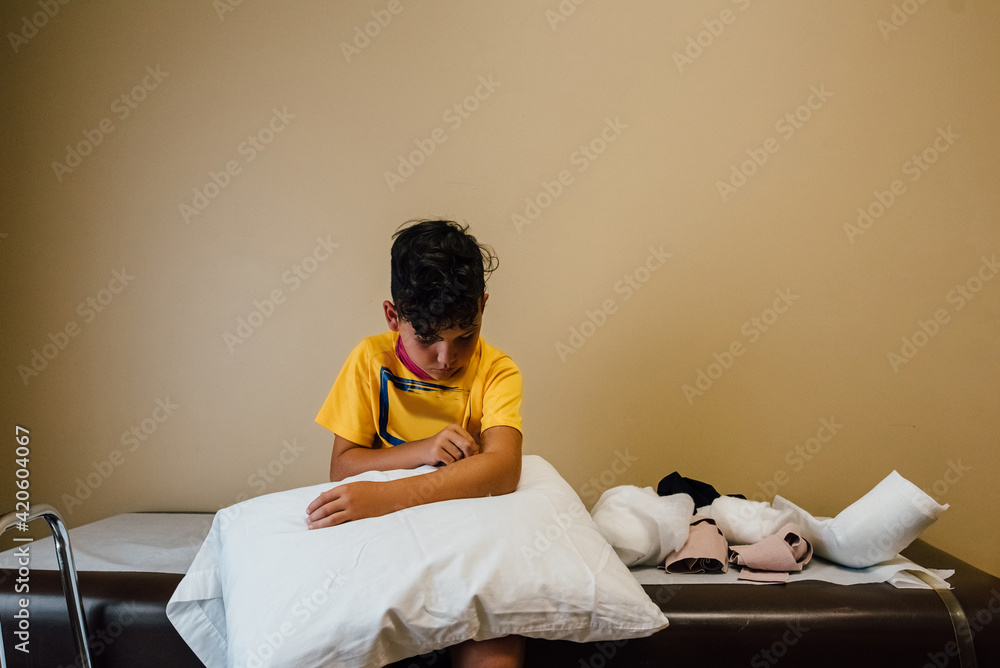 Boy sitting in doctor's office with a broken arm. Stock Photo | Adobe Stock