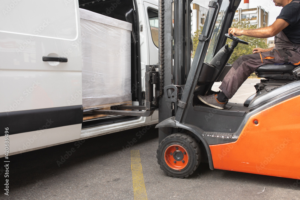 The worker transports freight into a van using a forklift Stock Photo ...