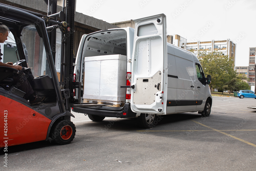 The worker transports freight into a van using a forklift Stock Photo ...