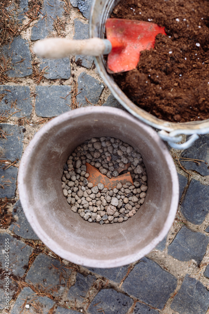 Foto Stock Putting clay pebbles and old pot shards on the bottom of ...