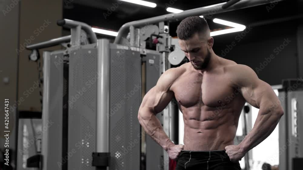 Bodybuilder athlete in peak shape in gym posing straining muscles of ...