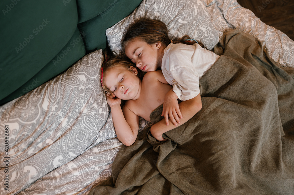 Cute sisters sleeping on bed together Stock Photo | Adobe Stock