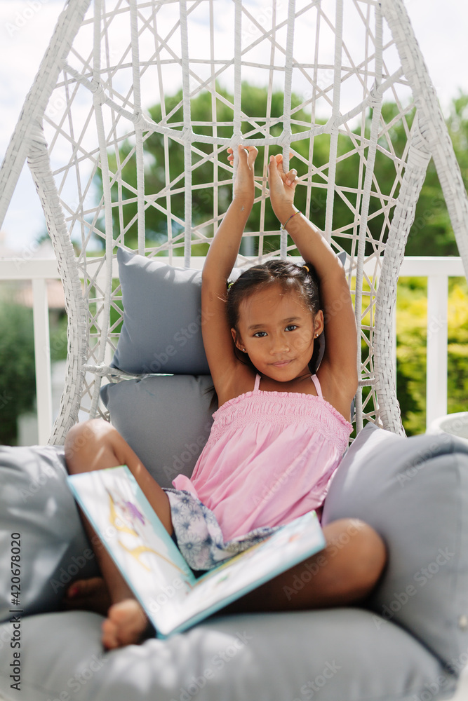 Kid reading in hanging chair Stock Photo | Adobe Stock