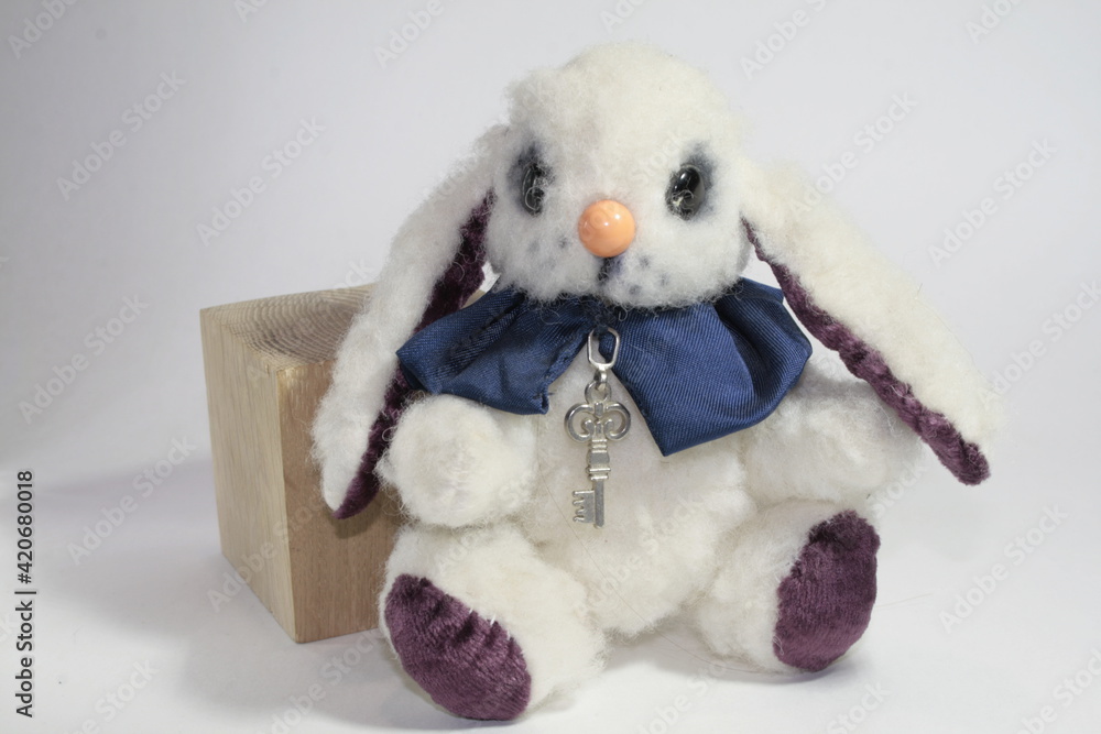 white plush rabbit toy with blue collar and vintage key on white ...